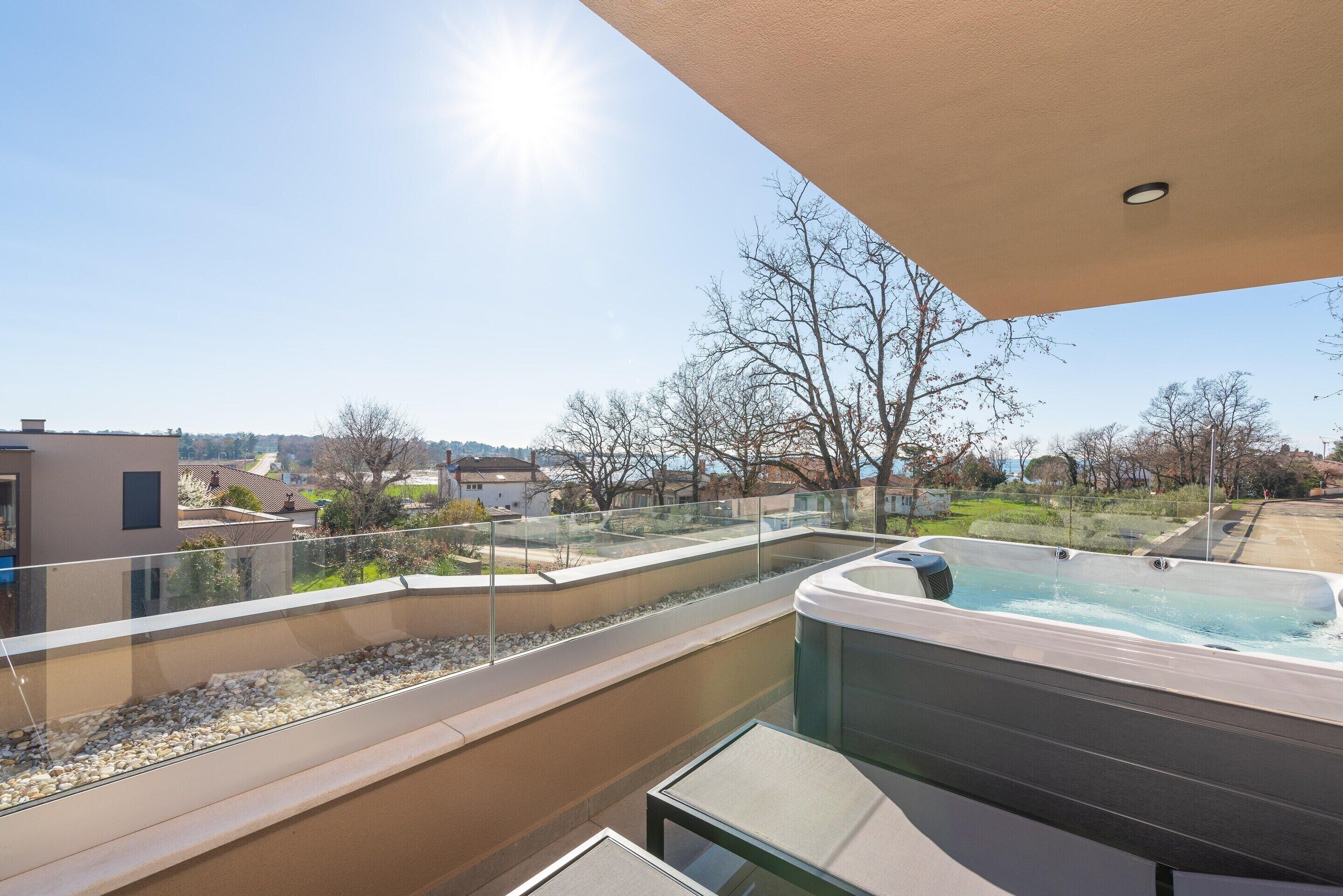 Terraço com hidromassagem, guarda-corpo de vidro e vista ampla do bairro.