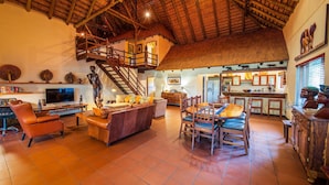 Uma sala de estar espaçosa com pé direito alto, uma mesa de jantar e uma cozinha.