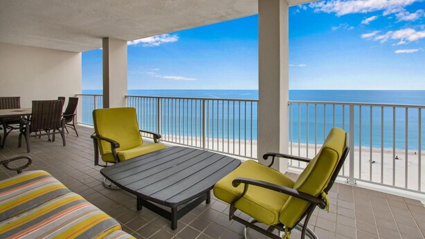 Varanda com vista para o oceano, com mesa e cadeiras.
