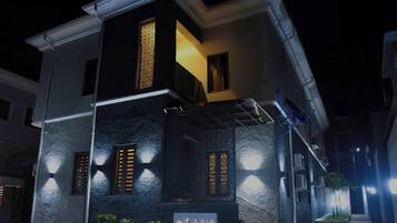 Um edifício moderno com fachada escura, janelas iluminadas e uma placa indicando um hotel.