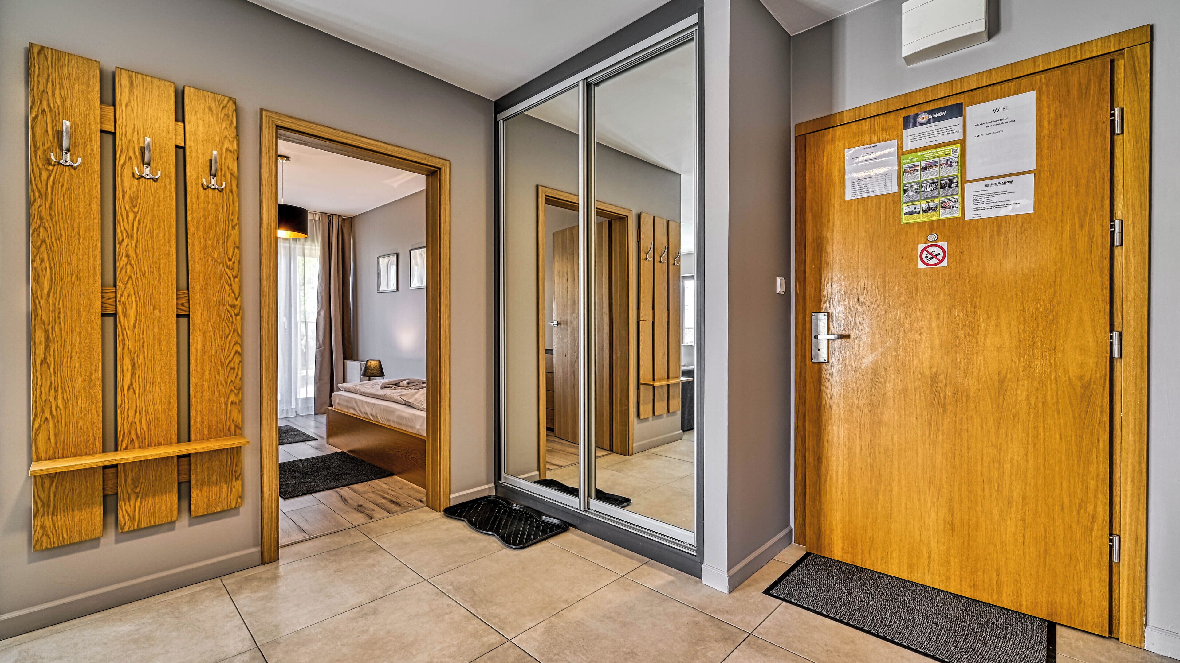 Corredor de hotel com painéis de madeira, um espelho e uma porta com a inscrição 'WiFi'.