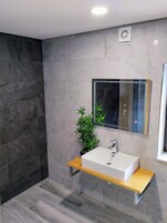 Uma casa de banho moderna com uma pia retangular, um espelho e uma planta em vaso.