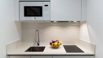 Uma cozinha moderna com micro-ondas embutido, uma pia de aço inoxidável e uma fruteira no balcão.