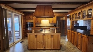 Uma cozinha em estilo cabana de madeira, com armários de madeira, uma ilha central e uma parede de pedra.