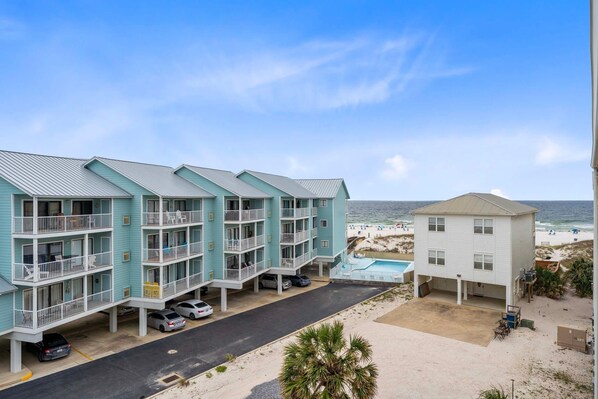 Hotel na praia com várias varandas, piscina e vista para o mar.