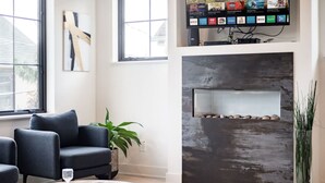 Uma sala de estar moderna com lareira, assentos confortáveis e uma TV de tela plana na parede.