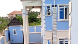 Um pátio com uma fonte, um edifício azul e uma escadaria.