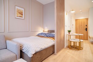 Quarto moderno com cama, mesa de cabeceira, abajur e uma pequena mesa redonda com cadeiras.