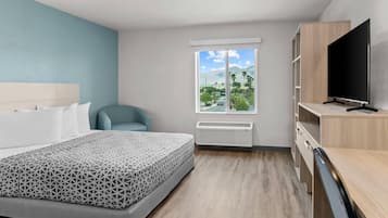 Quarto de hotel moderno com cama, televisão, escrivaninha e janela com vista para o exterior.