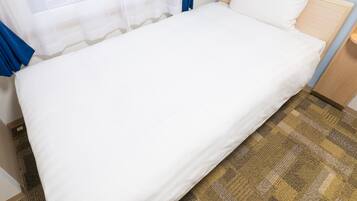Uma cama bem arrumada com lençóis brancos, cabeceira de madeira e tapete estampado.