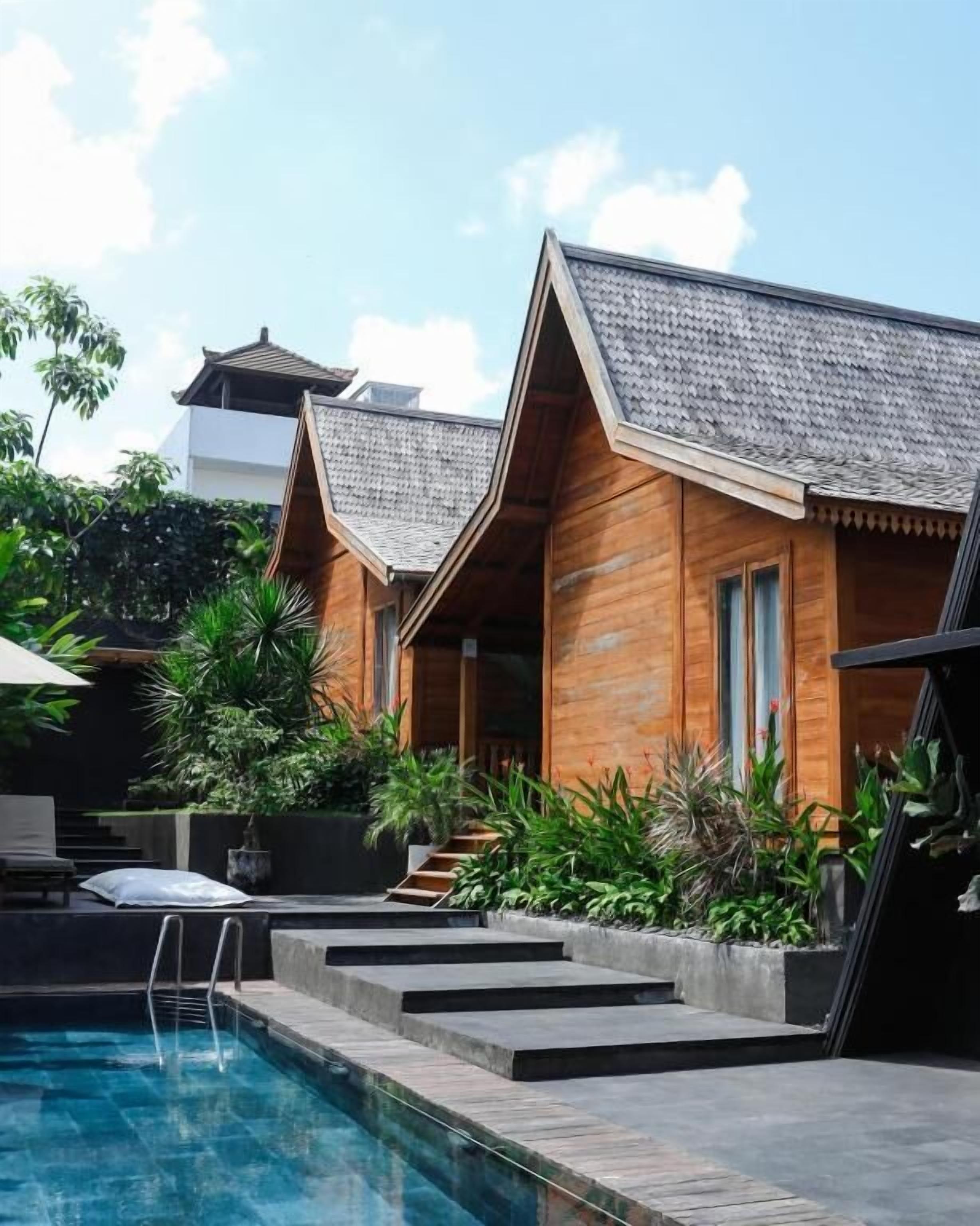 Uma casa moderna de madeira com telhado inclinado, piscina e jardim bem cuidado.