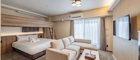 Quarto de hotel moderno com cama, sofá e televisão.