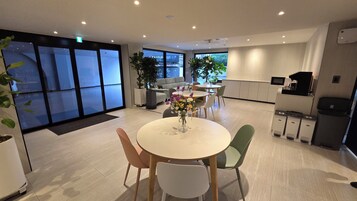 Quarto de hotel moderno com área de refeições, sofá e cozinha.