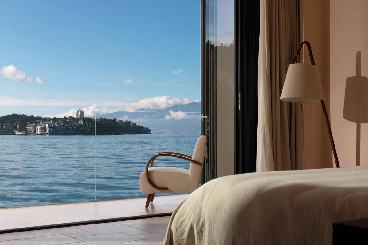 Quarto de hotel com uma janela grande que oferece vista para um corpo de água e uma ilha distante.