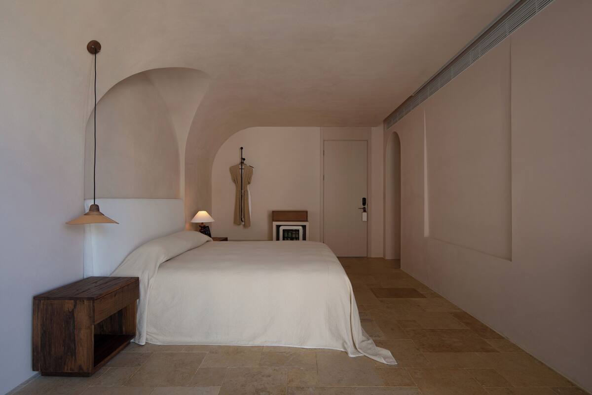 Quarto com cama grande, mesa de cabeceira, abajur e guarda-roupa.