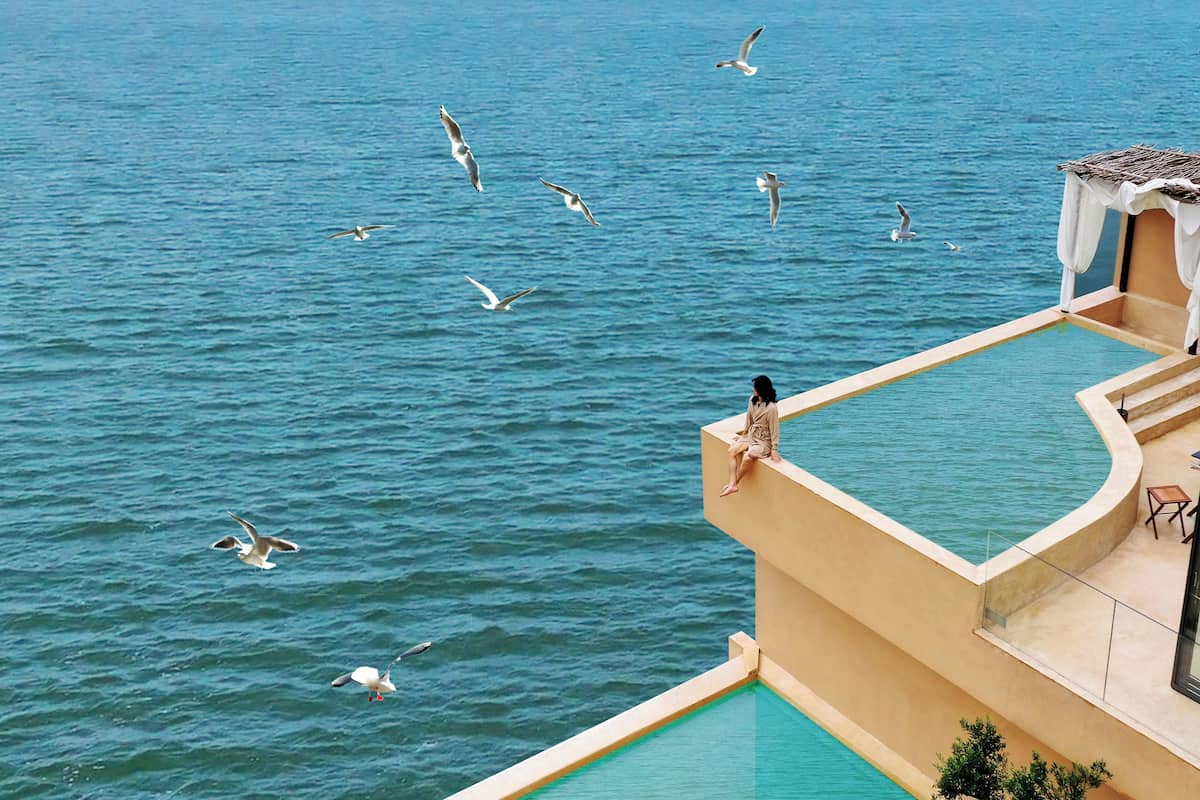 Uma varanda com vista para o mar e pássaros voando acima.