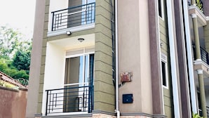 Um edifício residencial com vários andares, varandas, base de tijolos e telhado plano.