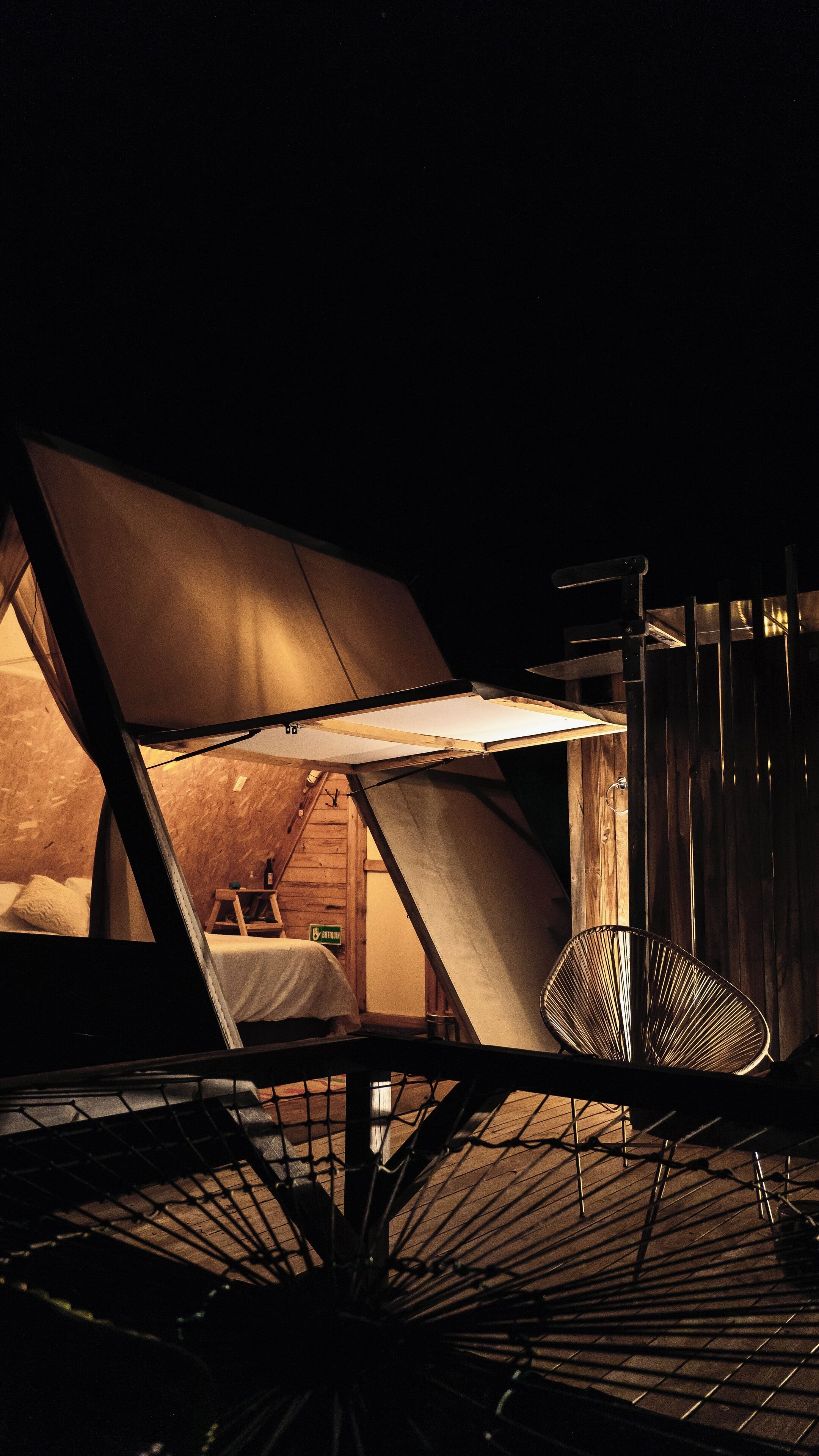 Alojamento em tenda com cama, cadeira e mesa.