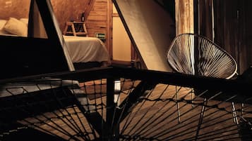 Alojamento em tenda com cama, cadeira e mesa.