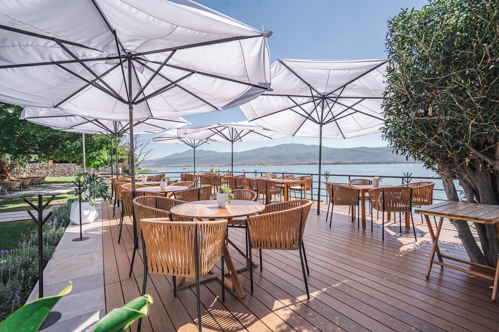 Um terraço com área de estar ao ar livre, guarda-sóis e vista para o mar.