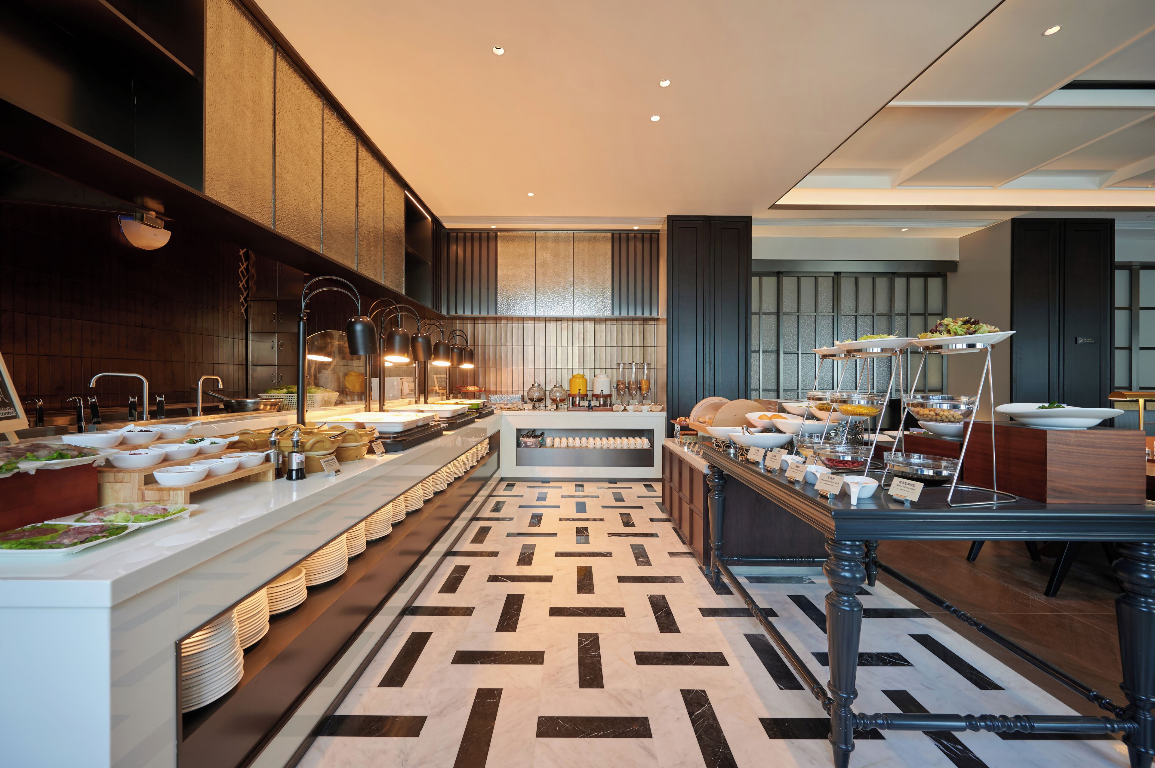 Disposição de buffet com várias estações de servir, piso estampado e design de interiores moderno.