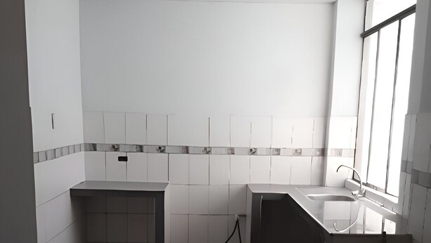 Um banheiro moderno com azulejos brancos, pia e janela.