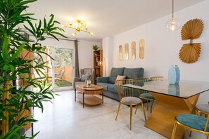 Uma sala de estar moderna com uma mesa de jantar de vidro, sofá verde e uma planta grande.