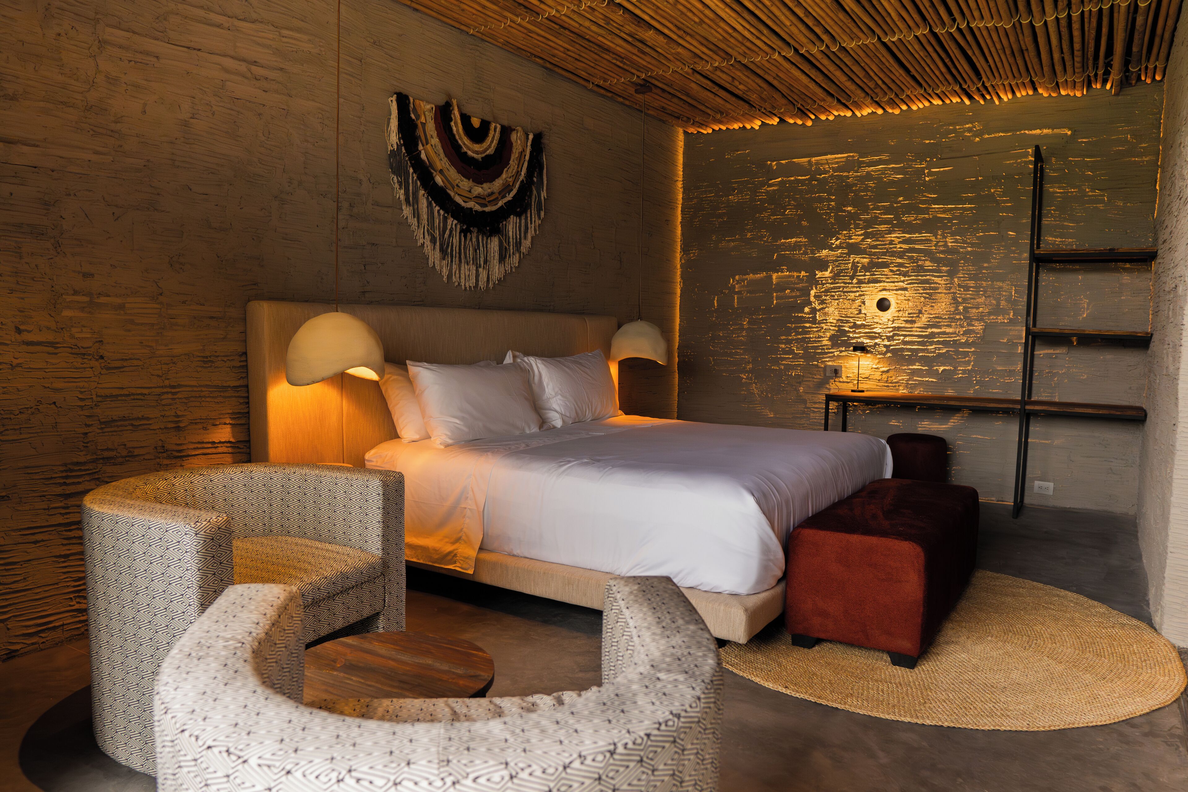 Um quarto moderno com uma cama grande, duas luminárias de cabeceira, uma obra de arte na parede e teto de madeira.