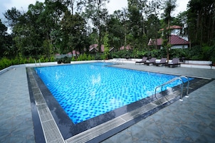 Piscina retangular com padrão de azulejos azuis, rodeada por um deck ladrilhado com espreguiçadeiras e uma pequena mesa.