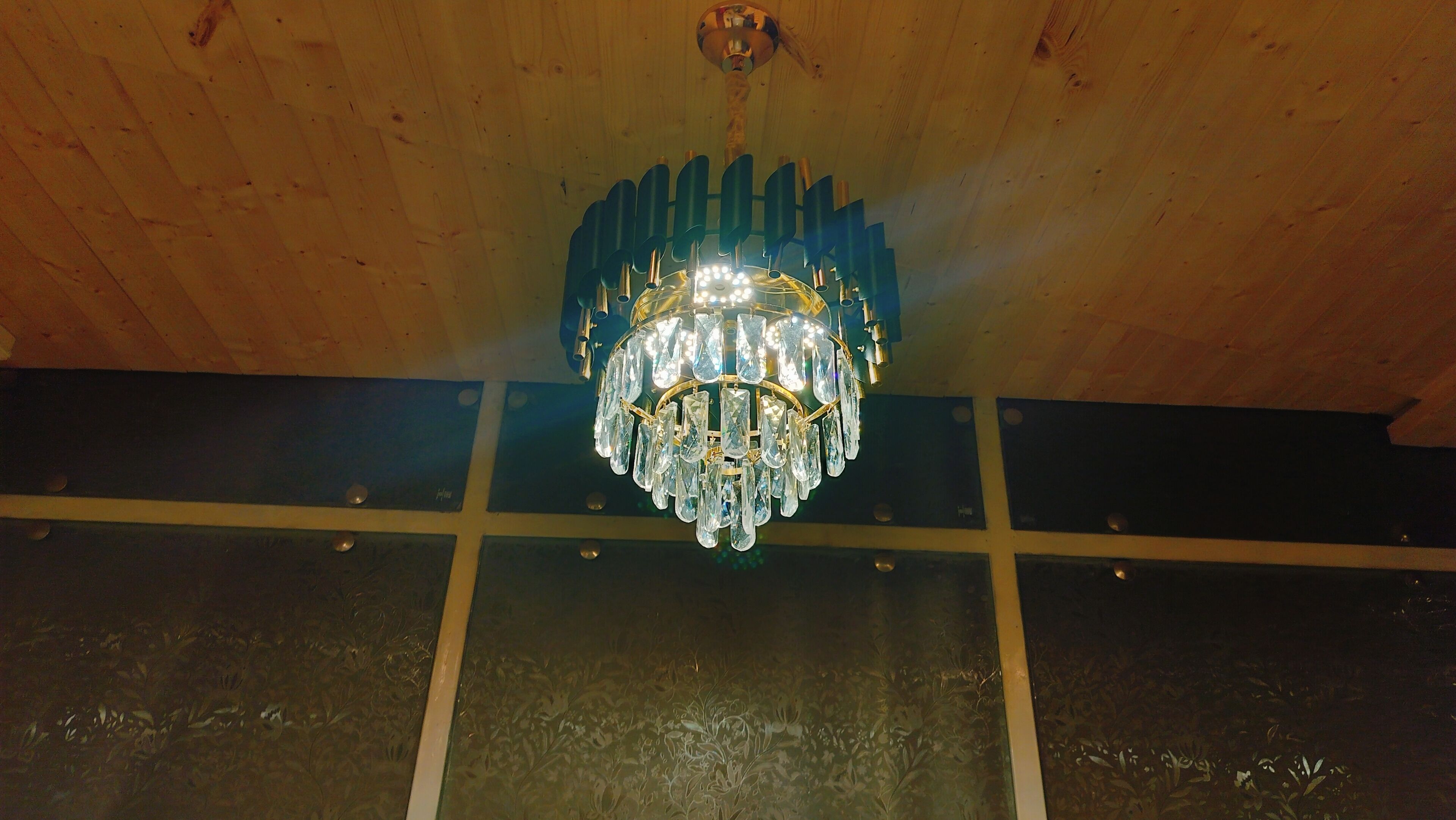 Um candelabro com vários elementos de cristal pendurados em um teto de madeira.