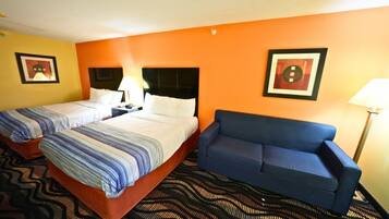 Quarto de hotel com duas camas, um sofá azul e um tapete estampado.