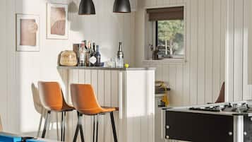 Quarto com mesa de bilhar, duas poltronas de couro, mesa de futebol de mesa e área de bar com garrafas e copos.