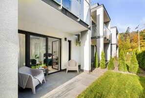 Um apartamento moderno com varanda, área de jantar e um pequeno jardim.