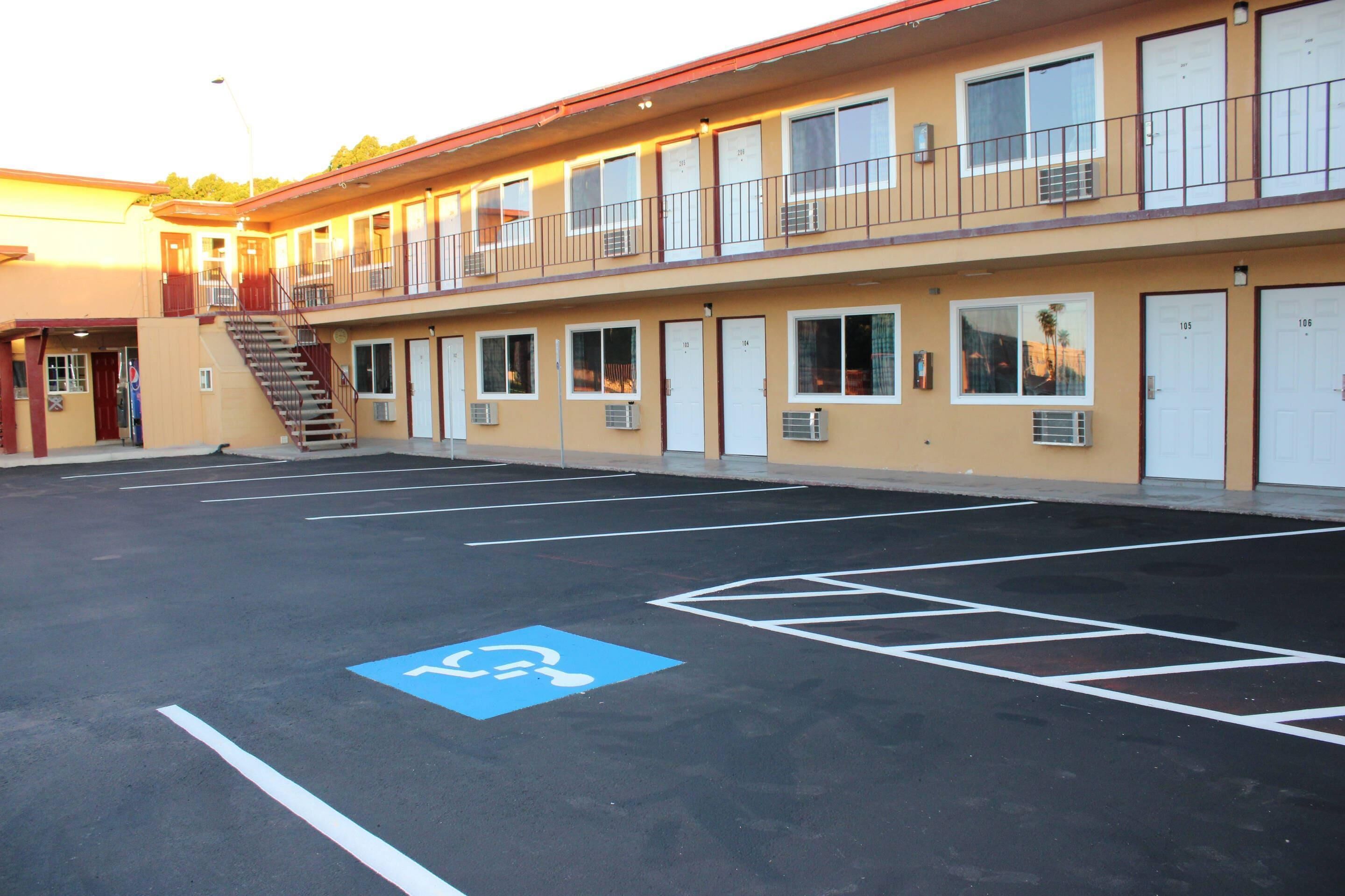 Um motel com estacionamento, incluindo vaga para deficientes.