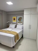 Quarto com cama, guarda-roupa e duas obras de arte emolduradas na parede.