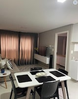 Um espaço compacto com área de refeições, sofá, televisão e cozinha compacta.