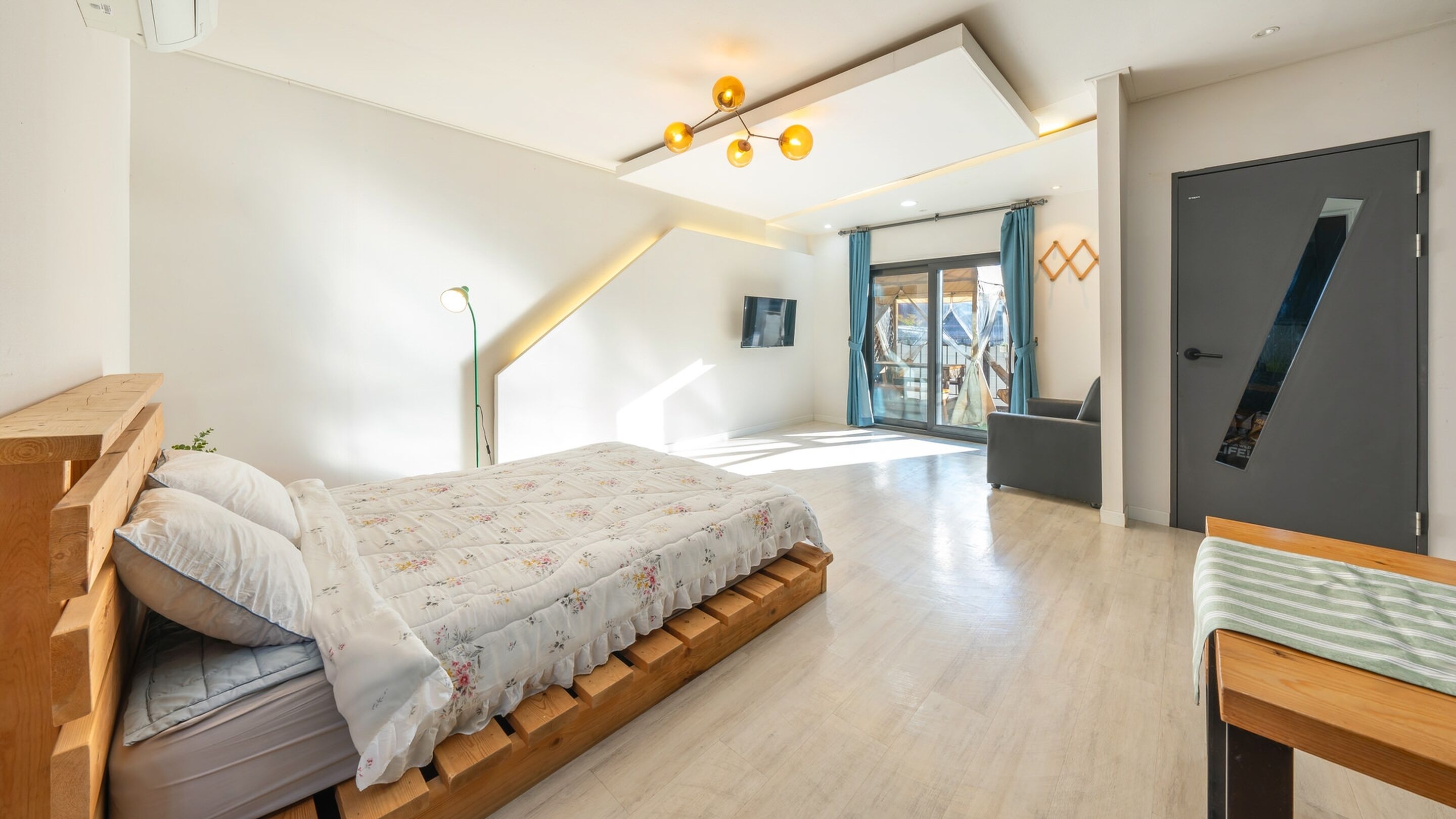 Quarto com beliche, escrivaninha, cadeira, televisão e porta com pôster.