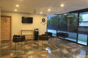 Um hall moderno com porta de vidro, televisão fixada na parede e cadeiras com padrão hexagonal.