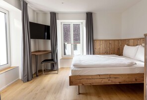 Um quarto moderno com uma cama de madeira, uma escrivaninha e uma televisão fixada na parede.