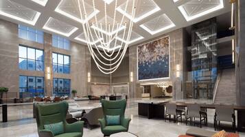 Um hall amplo com poltronas modernas verdes, um lustre grande e um teto alto com claraboias.