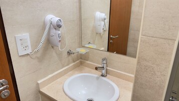 Uma casa de banho com uma pia, um secador de cabelo, um espelho e uma porta.
