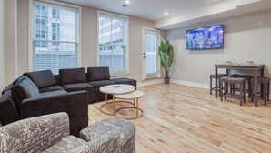 Uma sala de estar moderna com um sofá seccional, uma mesa de centro e uma TV fixada na parede.