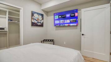 Quarto com cama, guarda-roupa, pintura e televisão com acesso a serviços de streaming.