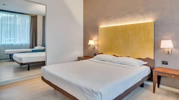 Quarto de hotel com uma cama grande, mesas de cabeceira, um espelho e uma luminária na parede.