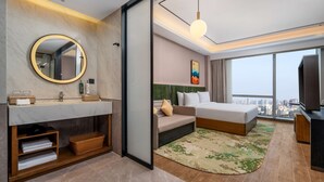 Quarto de hotel moderno com cama grande, área de estar, espelho redondo, televisão e vista para a cidade.