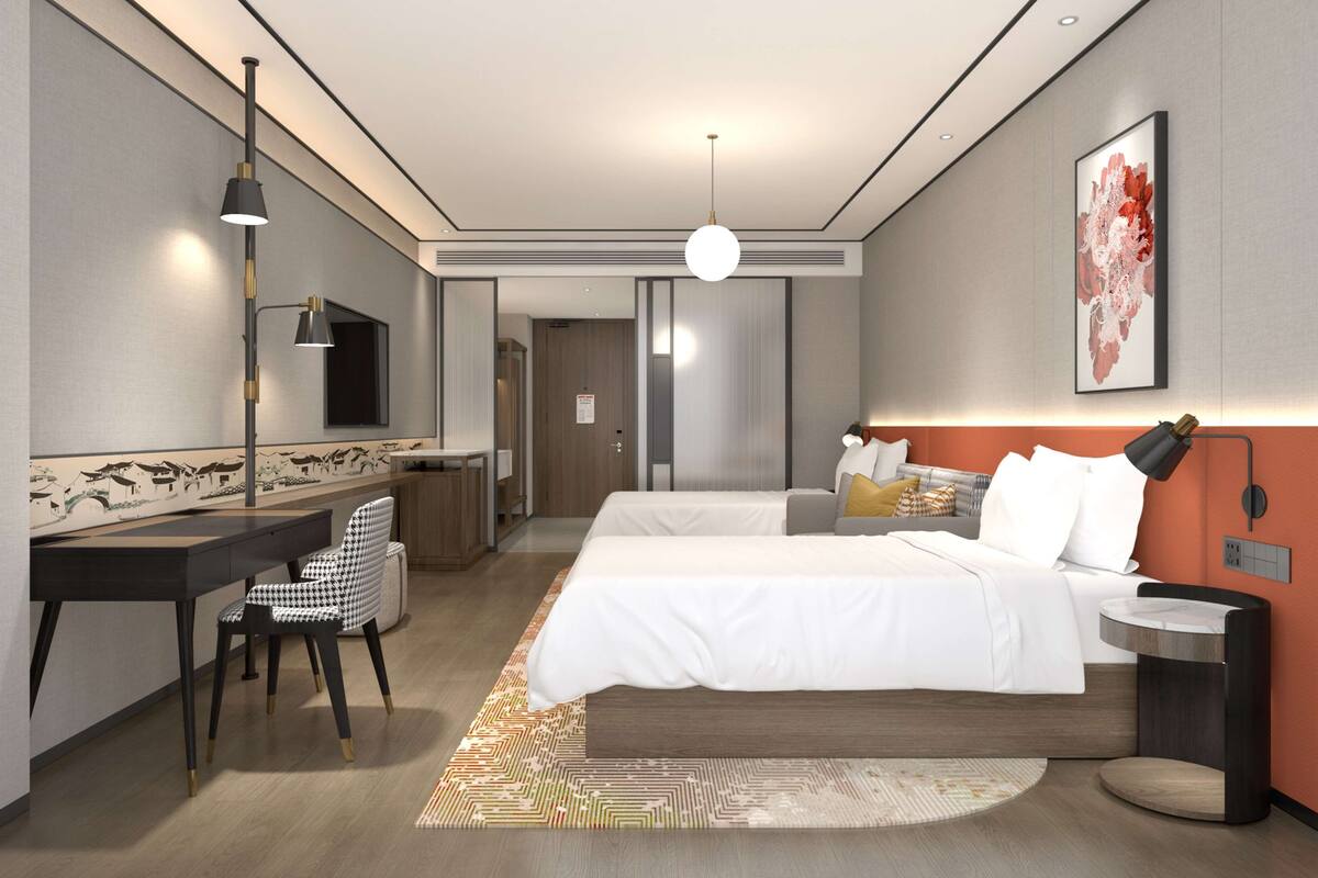 Quarto de hotel moderno com cama, escrivaninha, cadeira e uma grande janela.