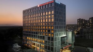 Um hotel moderno com uma placa de destaque Hilton Garden Inn, vários andares e uma área de entrada bem iluminada.