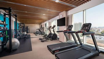 Uma academia com esteiras, bolas de exercício e aparelhos de musculação.