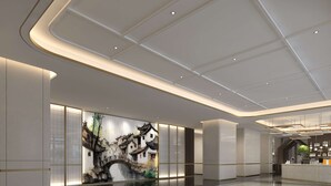 Um hall amplo com uma grande exposição de arte digital, um balcão de recepção e um chão de mármore polido.