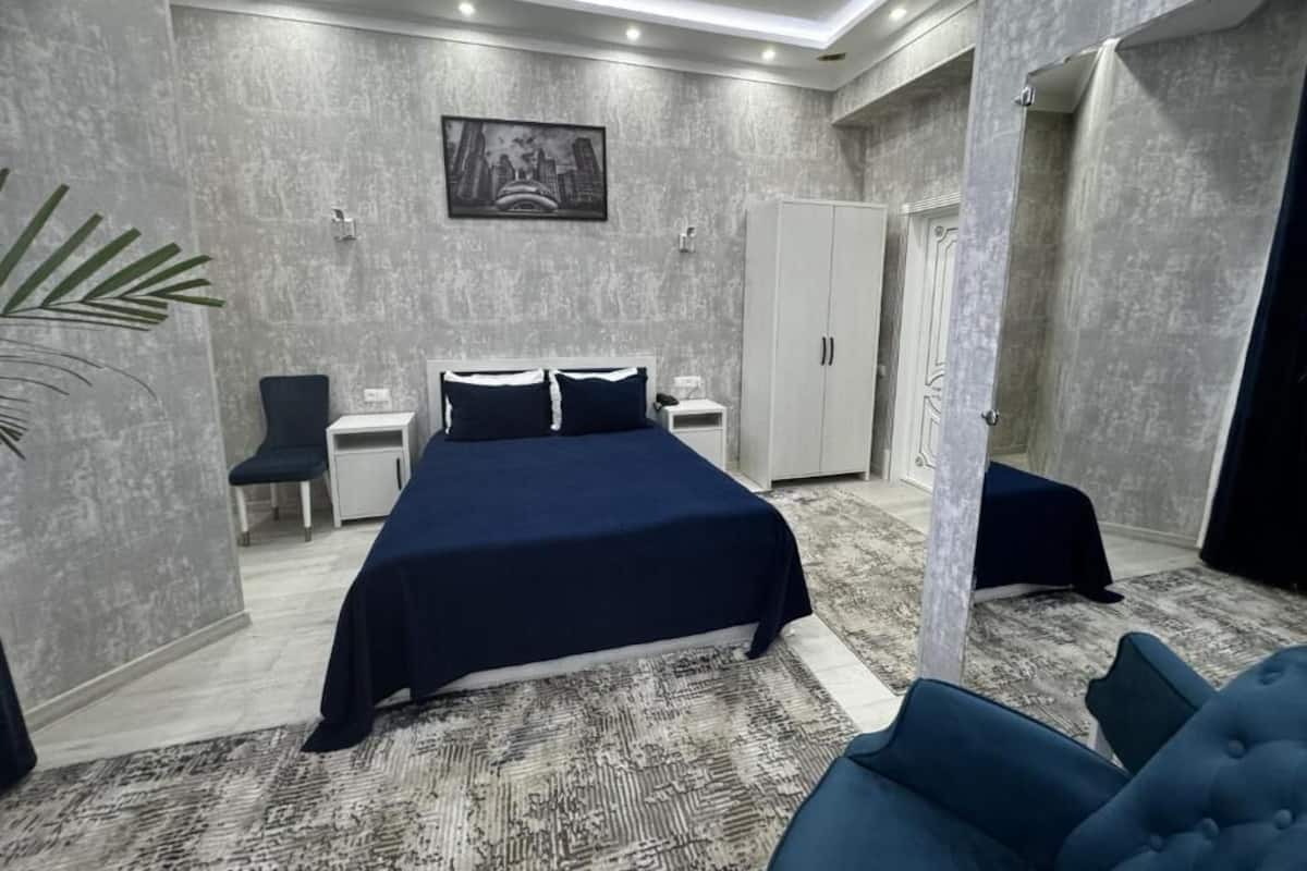 Um quarto com uma cama, mesas de cabeceira, guarda-roupa e uma cadeira.